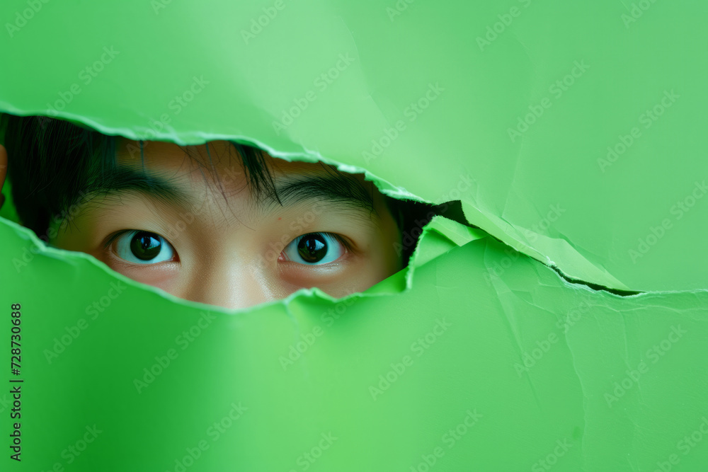 looking through paper. Mans green eye peering through through green ...