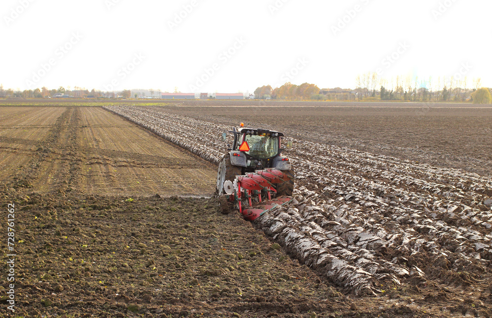 a farmer is ploughing with a turning plow in a clay field in the dutch ...