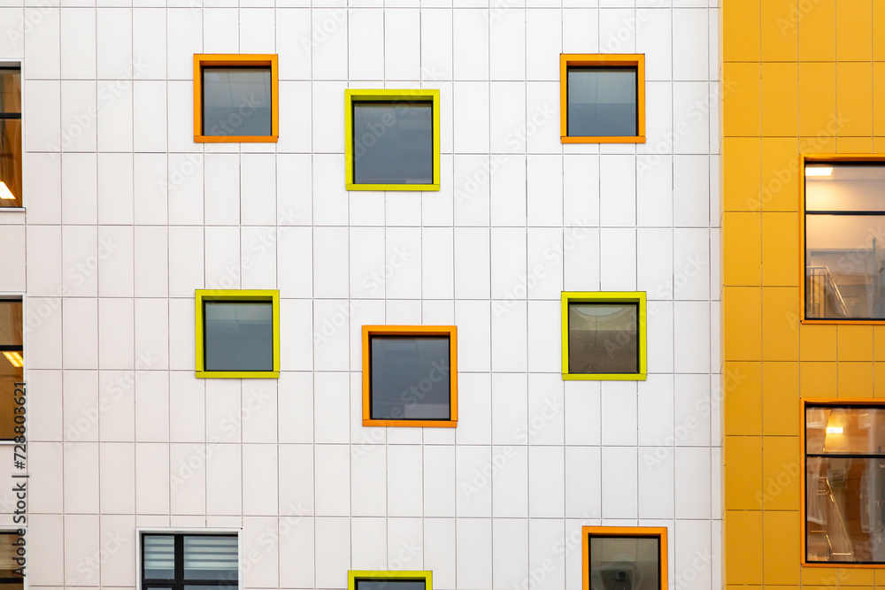 Multicoloured square windows on white wall of commercial building ...