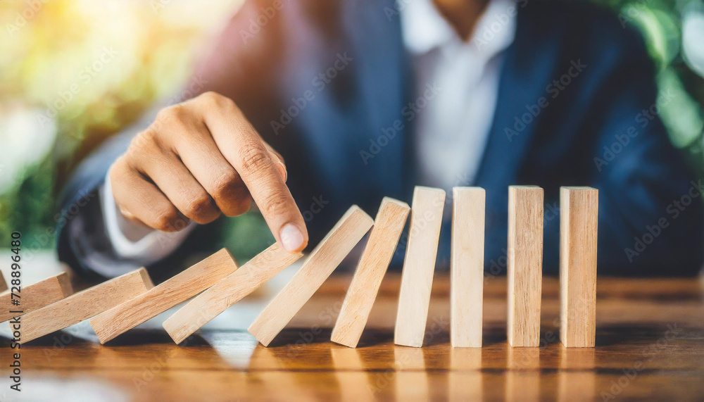 hand guards a wooden house from falling dominos with a protective ...