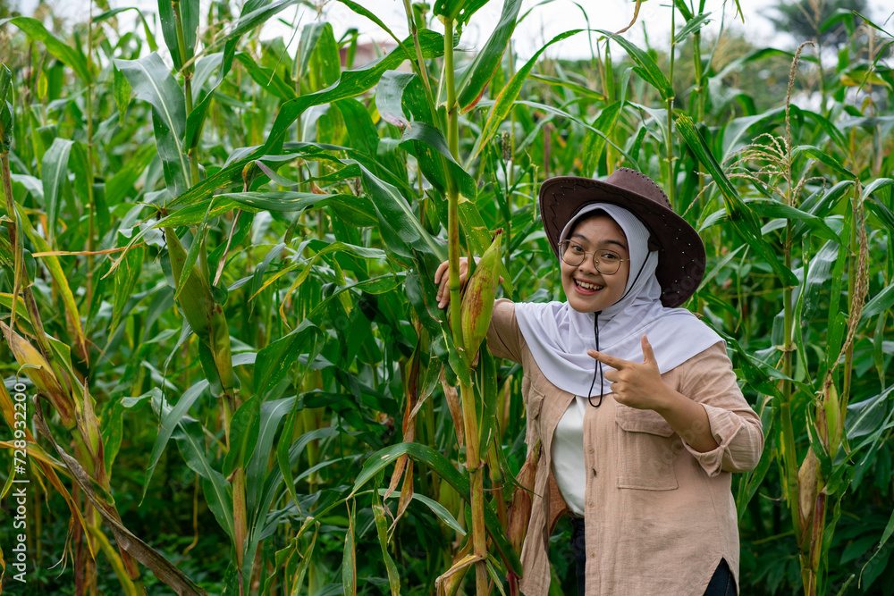 Young Asian female farmer who looks happy seeing her corn plants ...