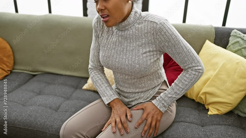 African american woman experiencing discomfort while sitting on a grey ...