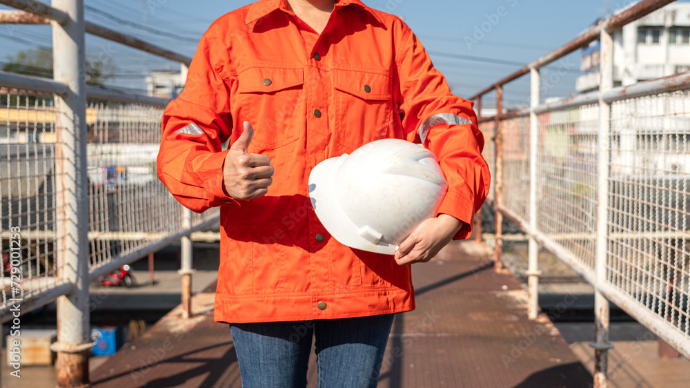 A construction foreman is orange working uniform and holding white ...