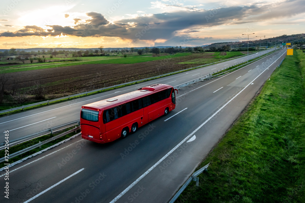 Red Modern comfortable tourist bus driving through highway at bright ...