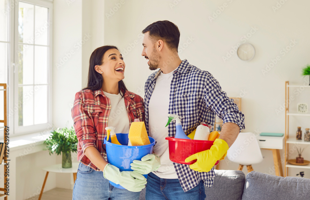Happy couple, armed with cleaning equipment, bringing joy to the living ...