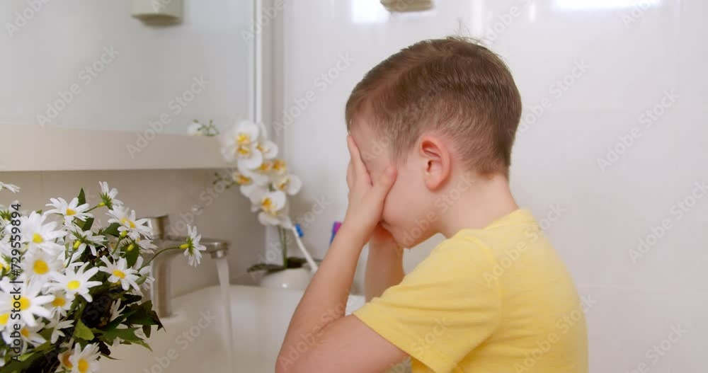 Child portrait of a happy cute little boy washing his face in the ...