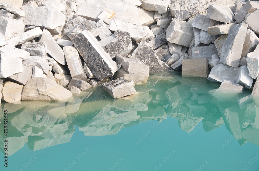 large limestone blocks falling into a brilliant green blue pool of ...