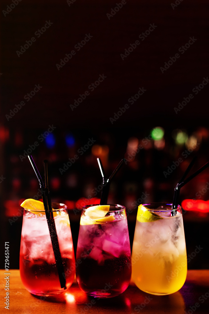 Three multi-colored alcoholic cocktails decorated with lime and oranges ...