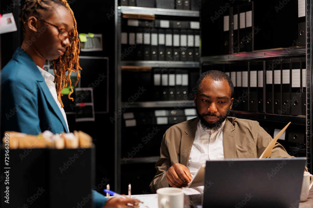 Detectives analyzing police report file and taking notes in office at ...