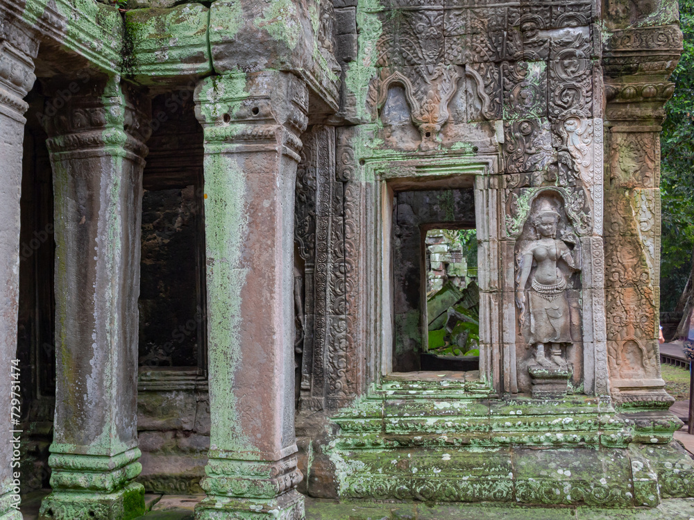 Moss-covered stone drawing picture carvings on a building wall at Ta ...