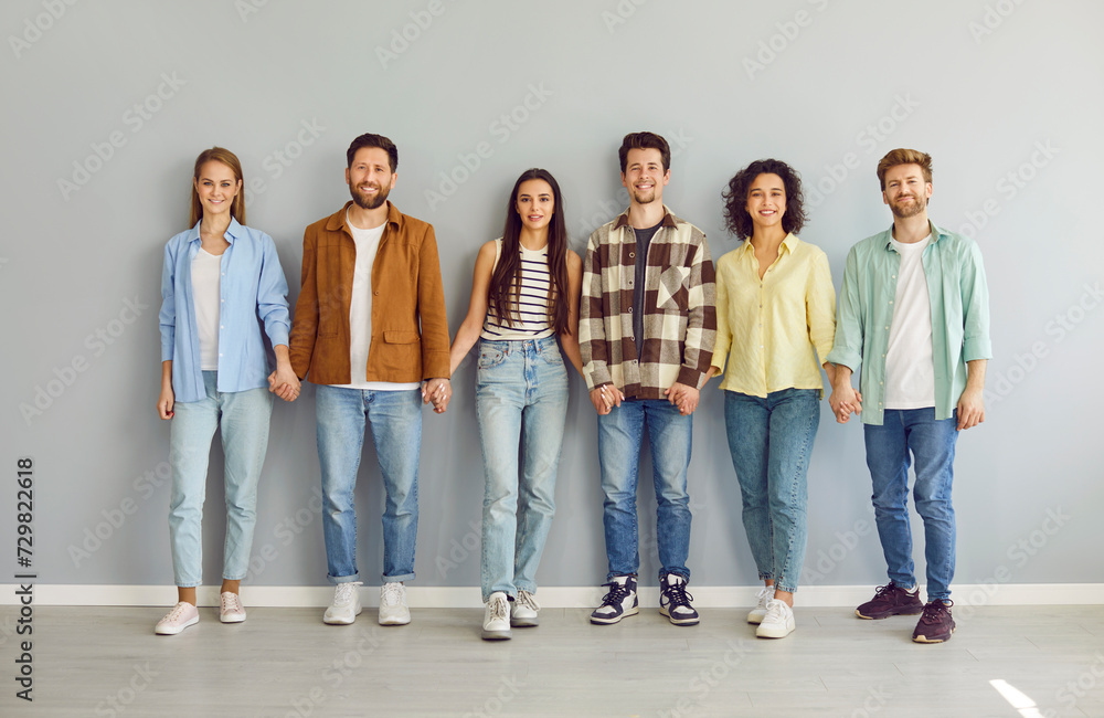 Team of young people in casual clothes standing by wall. Group of happy ...