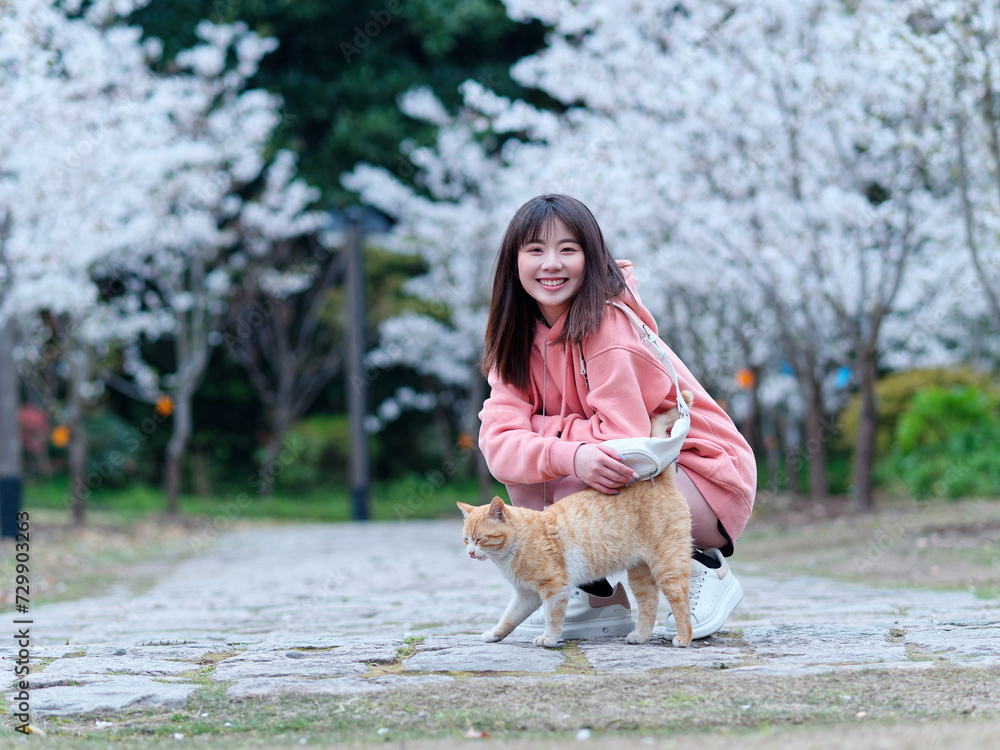 Beautiful young Chinese woman playing with homeless ginger tabby cat ...