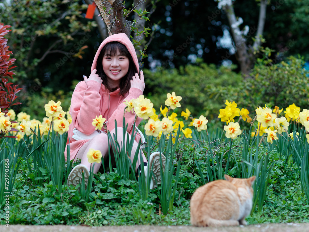 Beautiful young Chinese woman sitting in yellow daffodil flower field ...