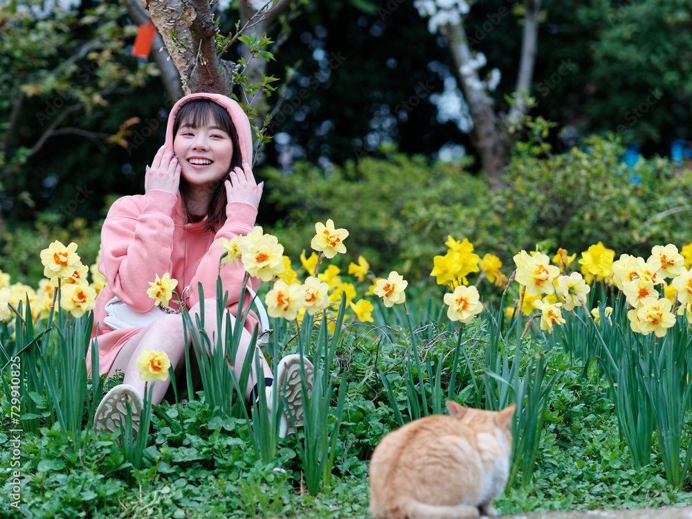 Beautiful young Chinese woman sitting in yellow daffodil flower field ...