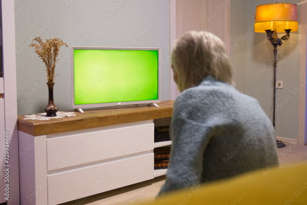 Grandma is watching TV. Green screen. Grandma is sitting on the sofa at ...