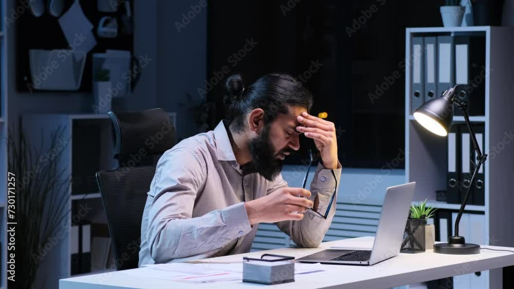 Weary, overworked Indian entrepreneur working with headache in late ...