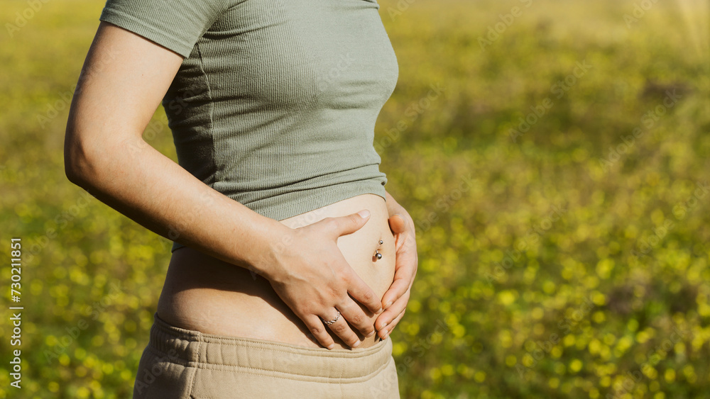 Belly of a pregnant woman in a field of flowers in spring in the first ...