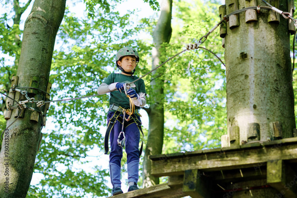 Two children in forest adventure park. Kids boys in helmet climbs on ...
