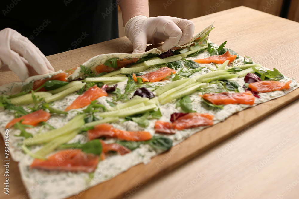 Lavash with filling is wrapped in a roll. Preparation of a roll with ...