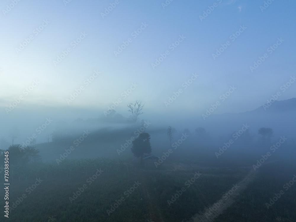 aerial view a sea of white mist envelops the mountain peak, slowly ...