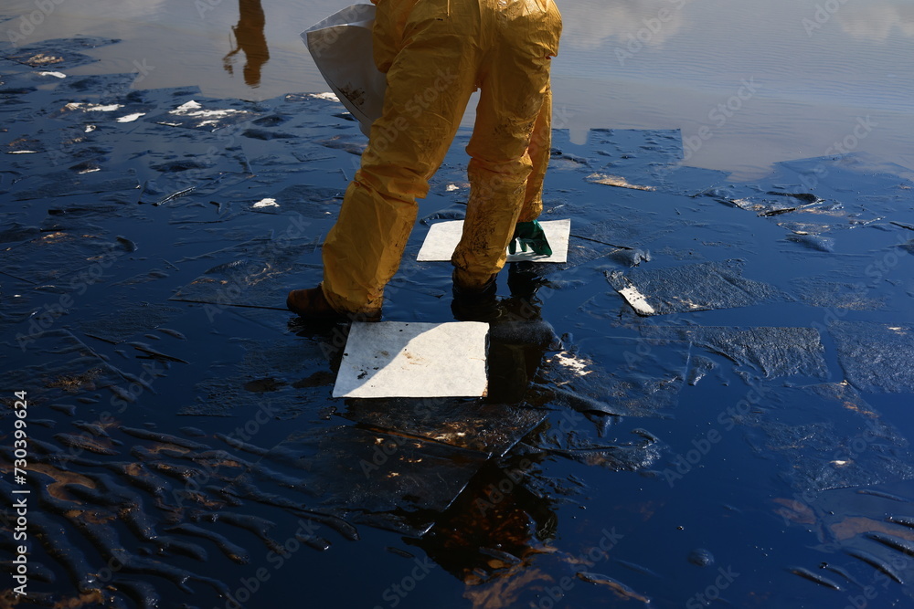 Professional team and volunteer wearing PPE clean up dirty of oil spill ...