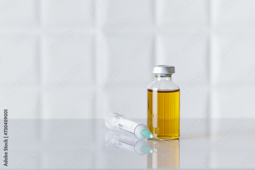 Glass bottle of injectable medicine and a syringe on white medical or ...