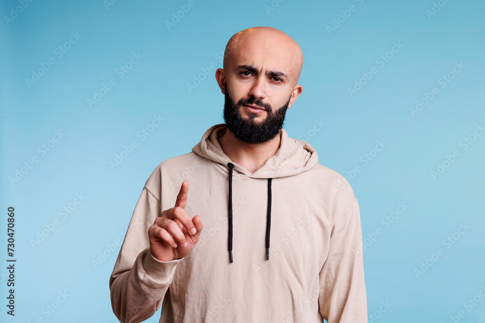 Serious arab man pointing at camera and showing one studio portrait ...