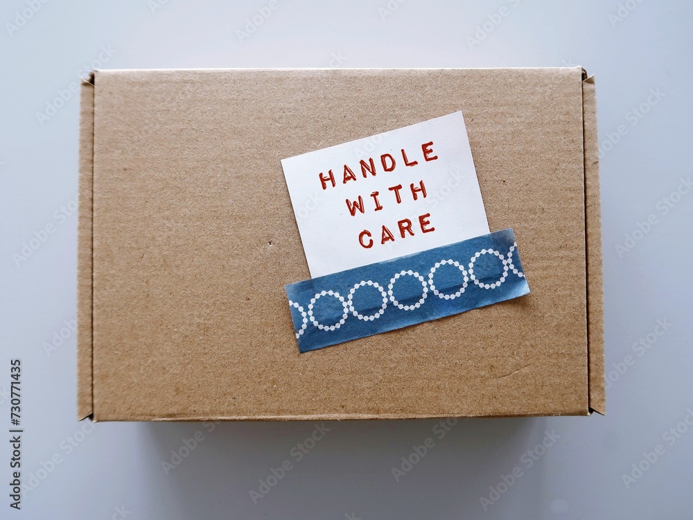 Delivery box with sticky text note written HANDLE WITH CARE, warning ...