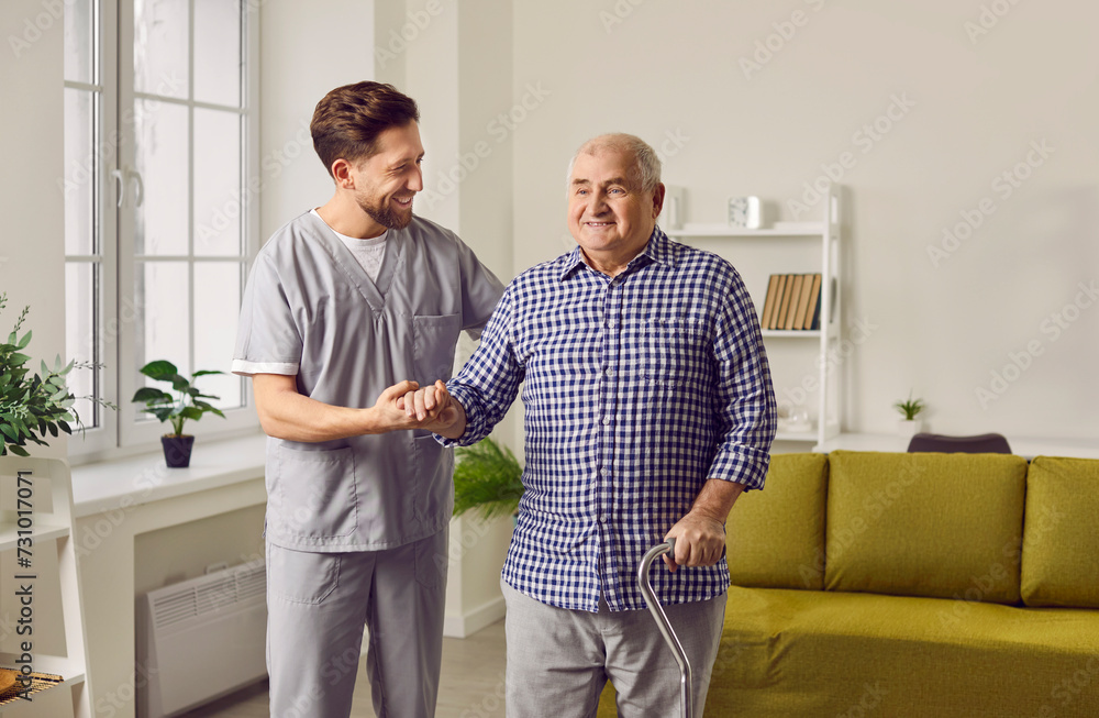Young caring male nurse helping senior man to walk. Man friendly carer ...
