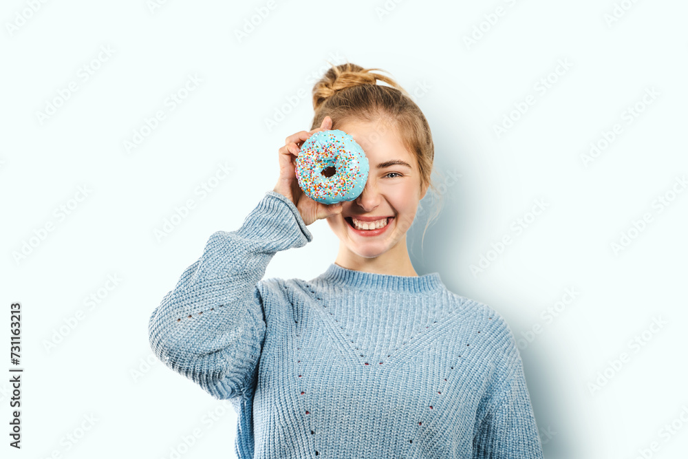 Young positive smiling laughing woman covers one eye with a blue donut ...