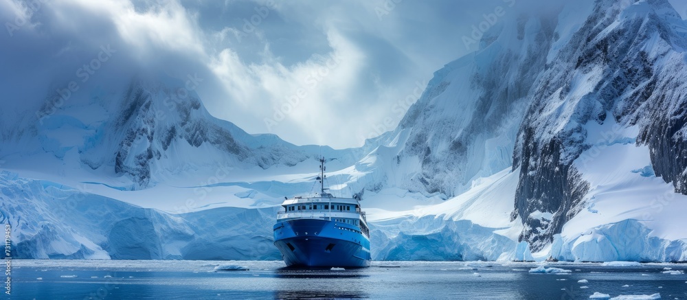 Blue expedition vessel in front of Antarctic iceberg landscape in ...