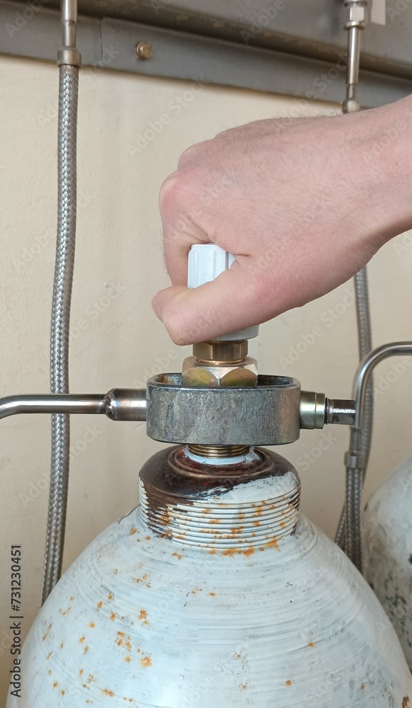 An employee's hand opens the valve of an acetylene cylinder against the ...