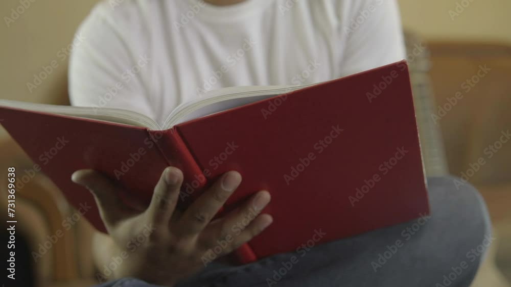 unrecognisable latin man holding and reading a book, turning pages and ...