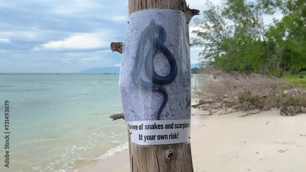 Beware of snakes and scorpions warning sign on a tropical beach, with ...