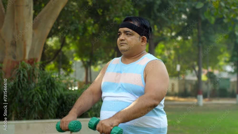 An Indian overweight man performing a workout in open gym - dumbbell ...