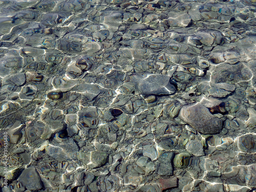Pebble rocks in the crystal clear water with shadow line, see through ...