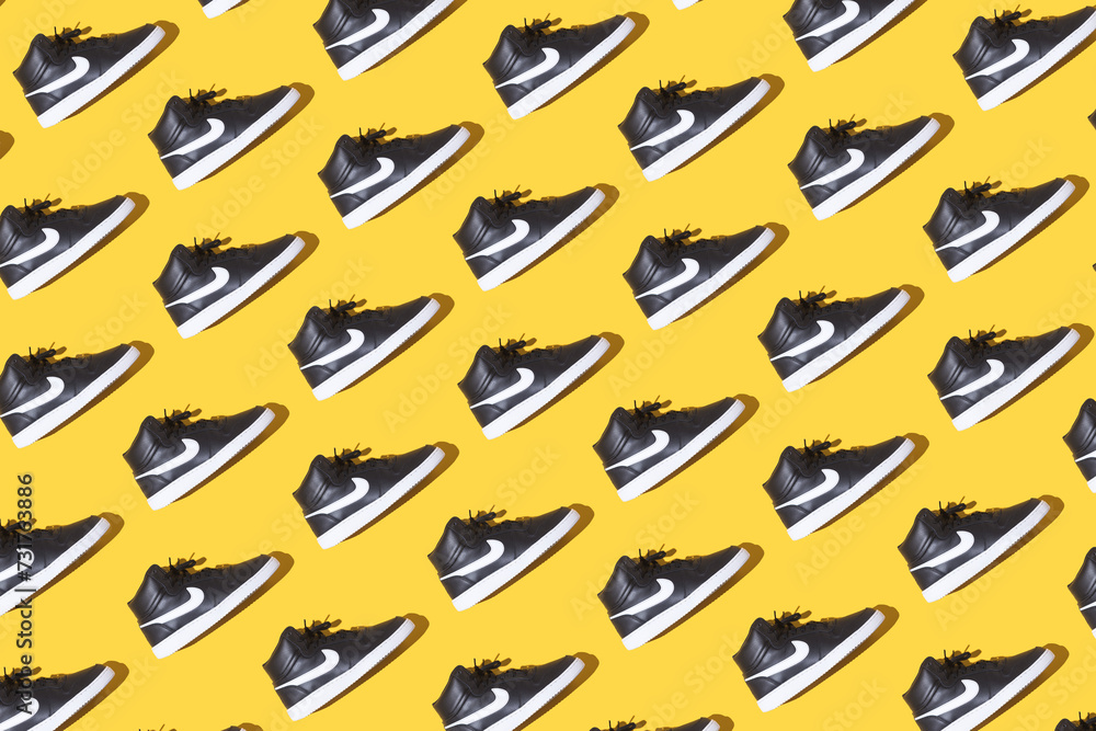 Pattern of black NIKE boot sneakers with the logo in white, on a yellow ...