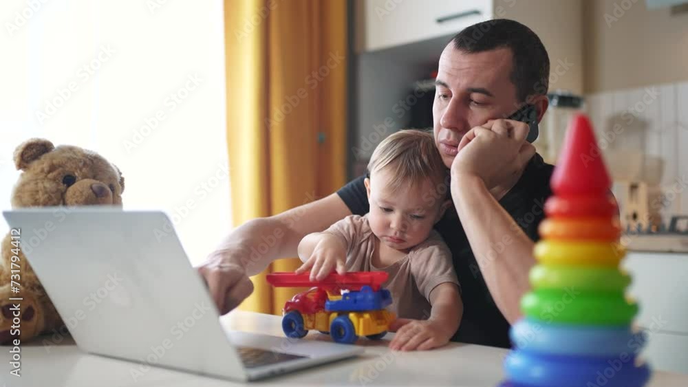 father working from home a remotely with baby son in his arms. pandemic ...
