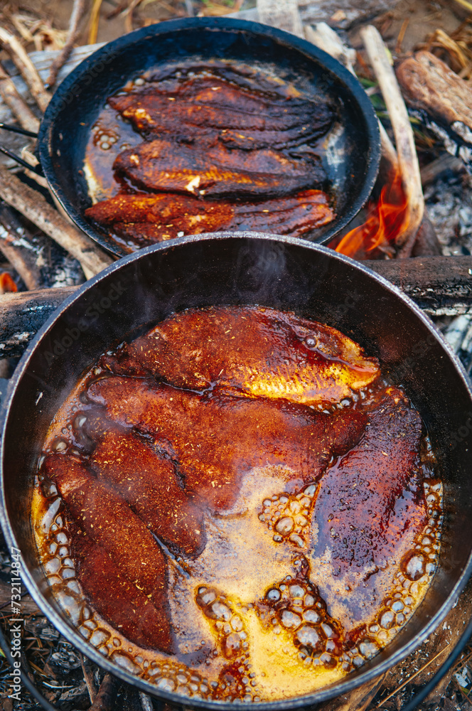 Blackened catfish fillets crackle in bacon fat over an open fire on the ...