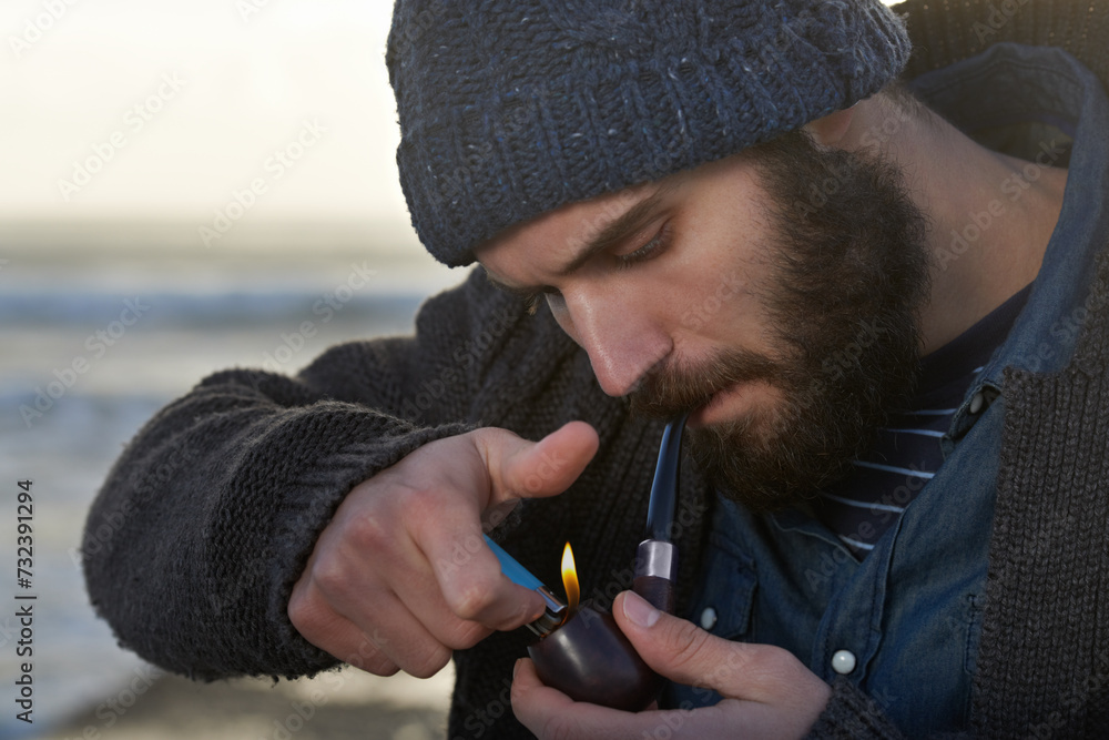 Bearded, man and smoking a pipe on beach, lighter and tobacco habit on ...