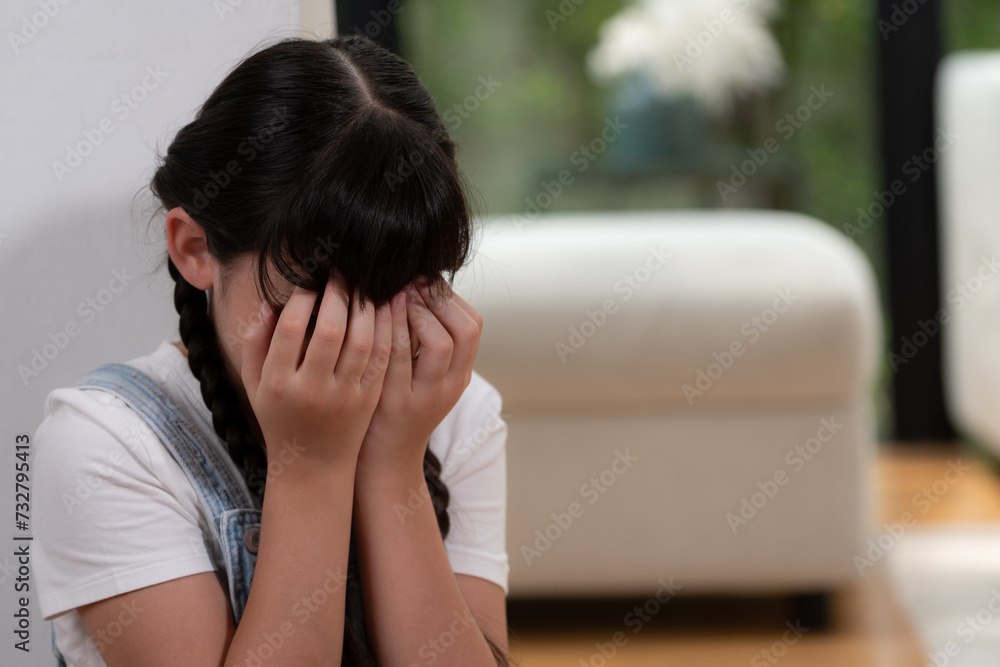 Sad little girl sitting alone in living room crying, feeling lonely ...
