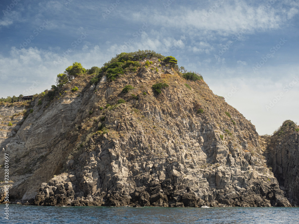 Weathered seaside rock face texture with parts of green and blue water ...