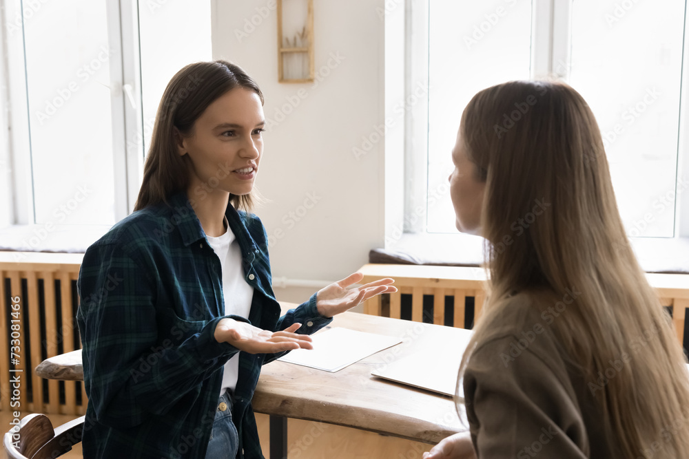 Positive young startup manager woman talking to colleague at workplace ...