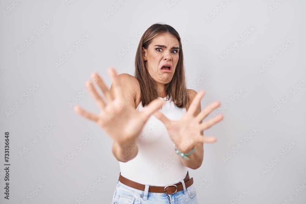Hispanic young woman standing over white background afraid and ...