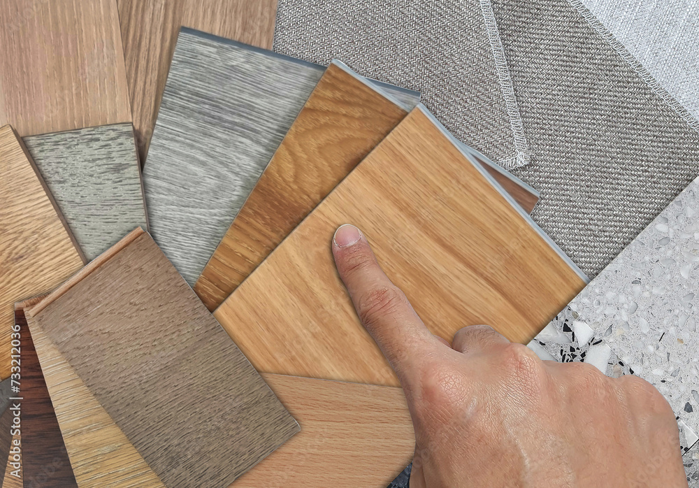 architect's hand selects collection of wooden interior material samples ...