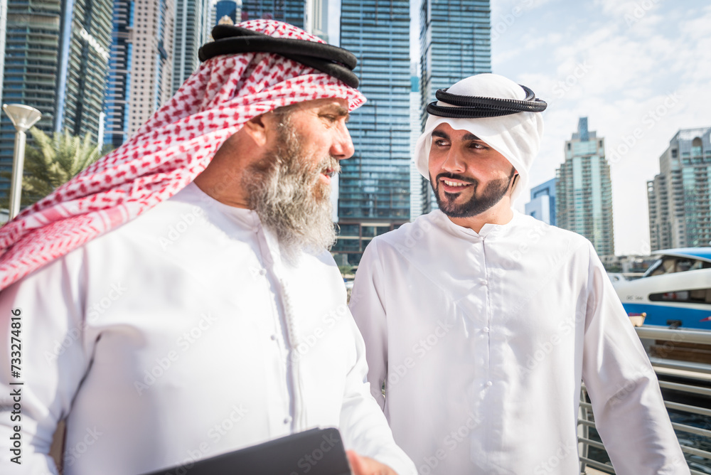 Arab businessmen wearing traditional emirati kandora meeting outdoors ...