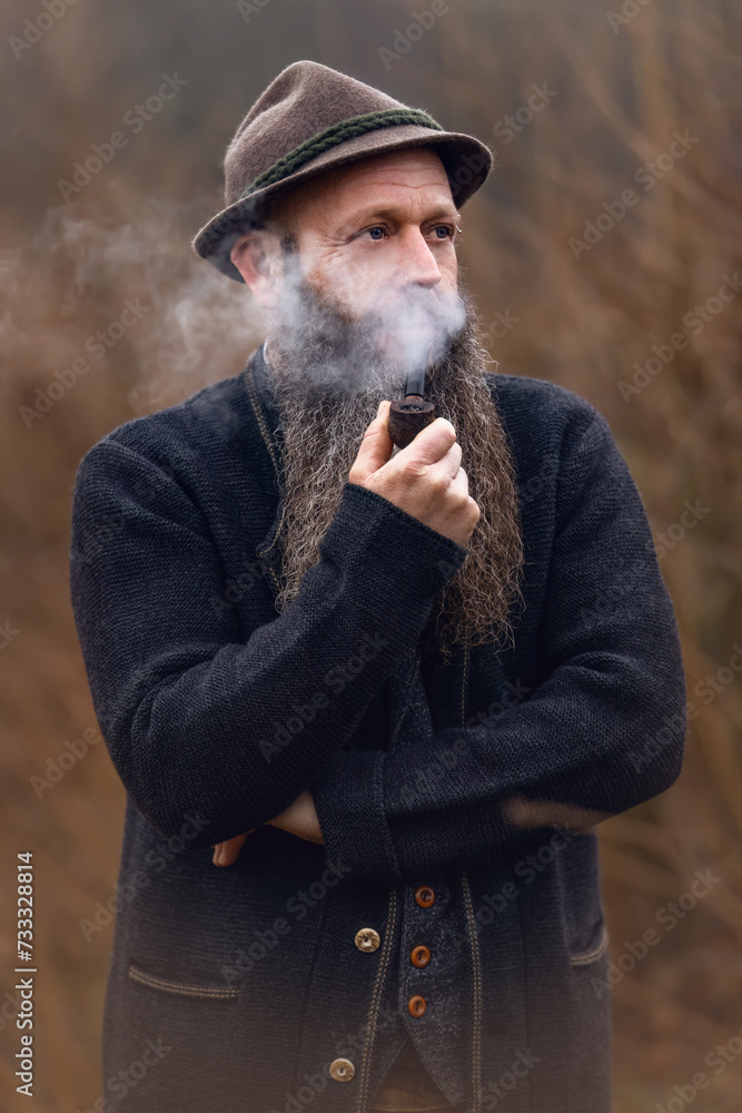 Portrait of a typical bavarian man smoking a pipe and wearing a ...