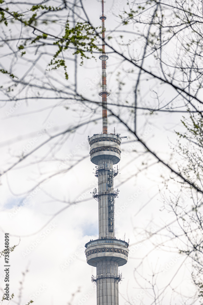 view of tv-tower through the tree branches. antenna-mast structure in ...