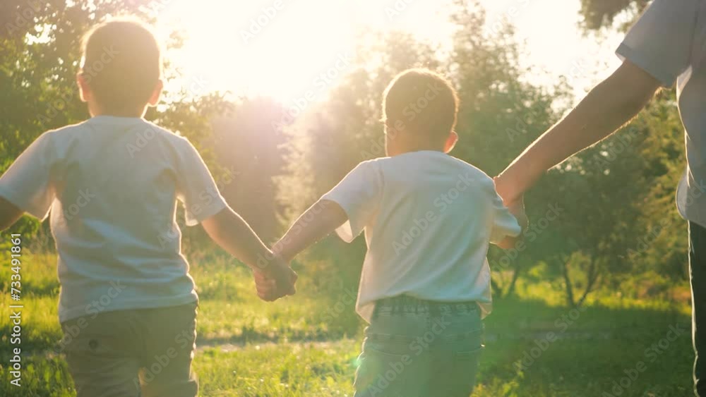 Friendly family with children runs holding hands across field in summer ...