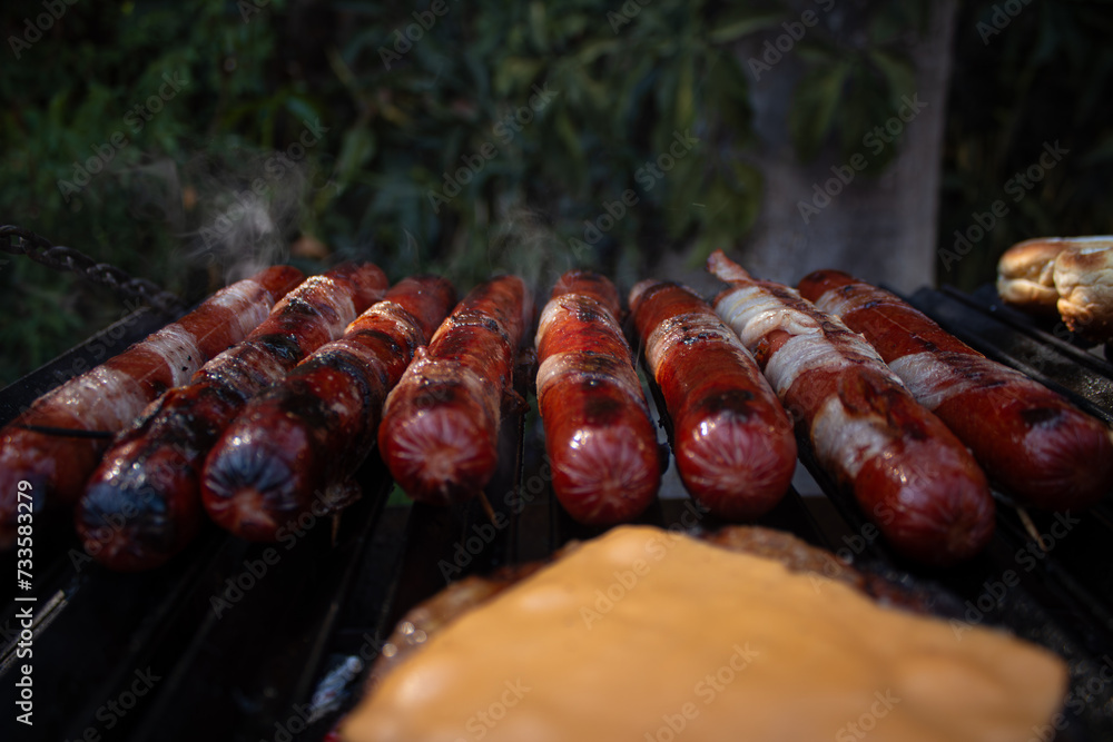 BBQ time with Bacon Wrapped Hot Dogs on a Charcoal Grill. The hot dogs ...